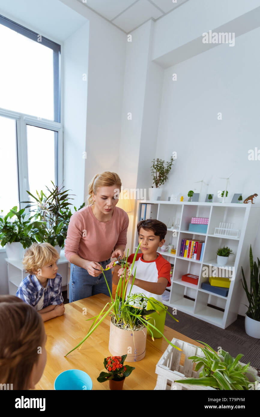 Cutting dry edges. Blonde-haired young teacher and schoolboy cutting ...