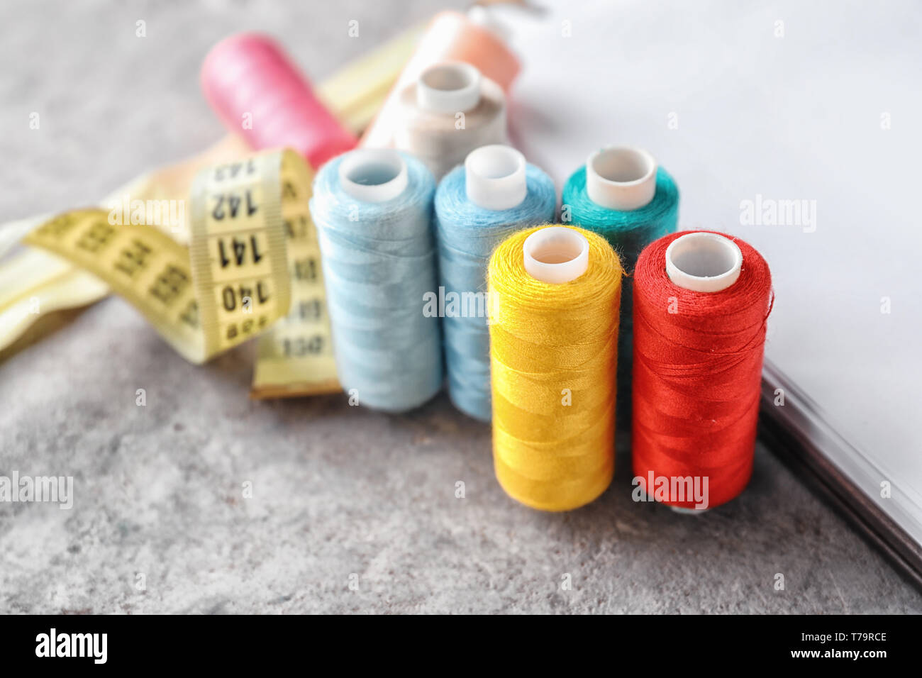 Sewing threads and measuring tape on grey background Stock Photo - Alamy