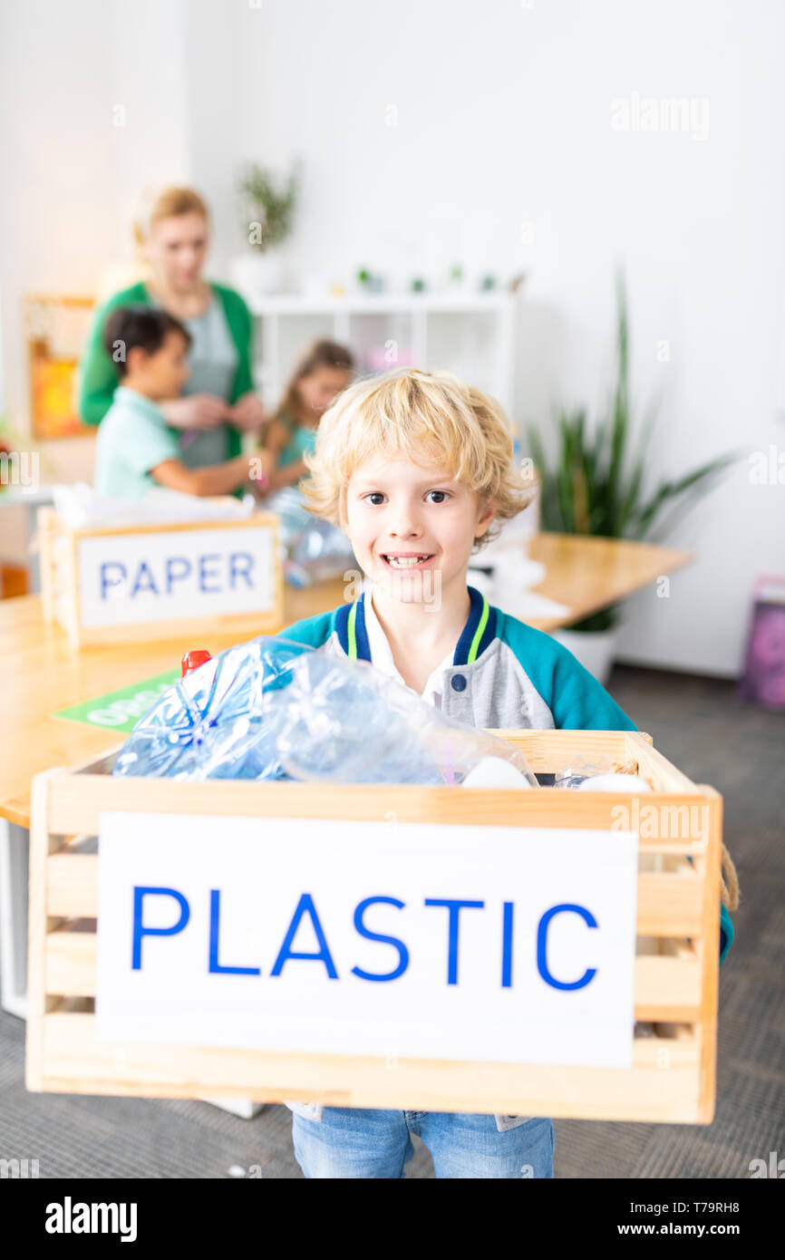 After sorting waste. Handsome funny schoolboy holding box with plastic ...