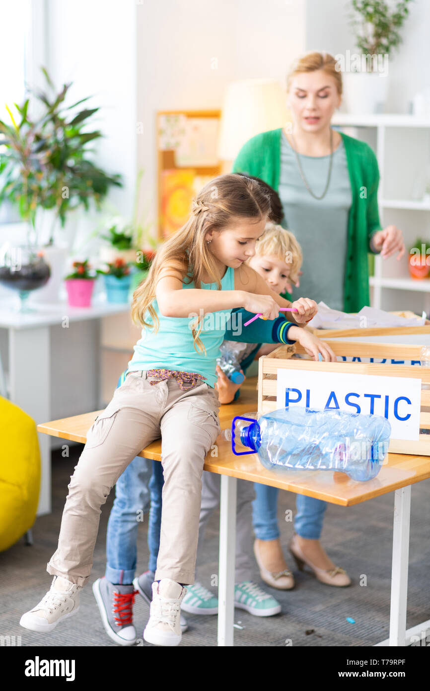 Sorting plastic. Beautiful girl sitting on table at school and sorting ...