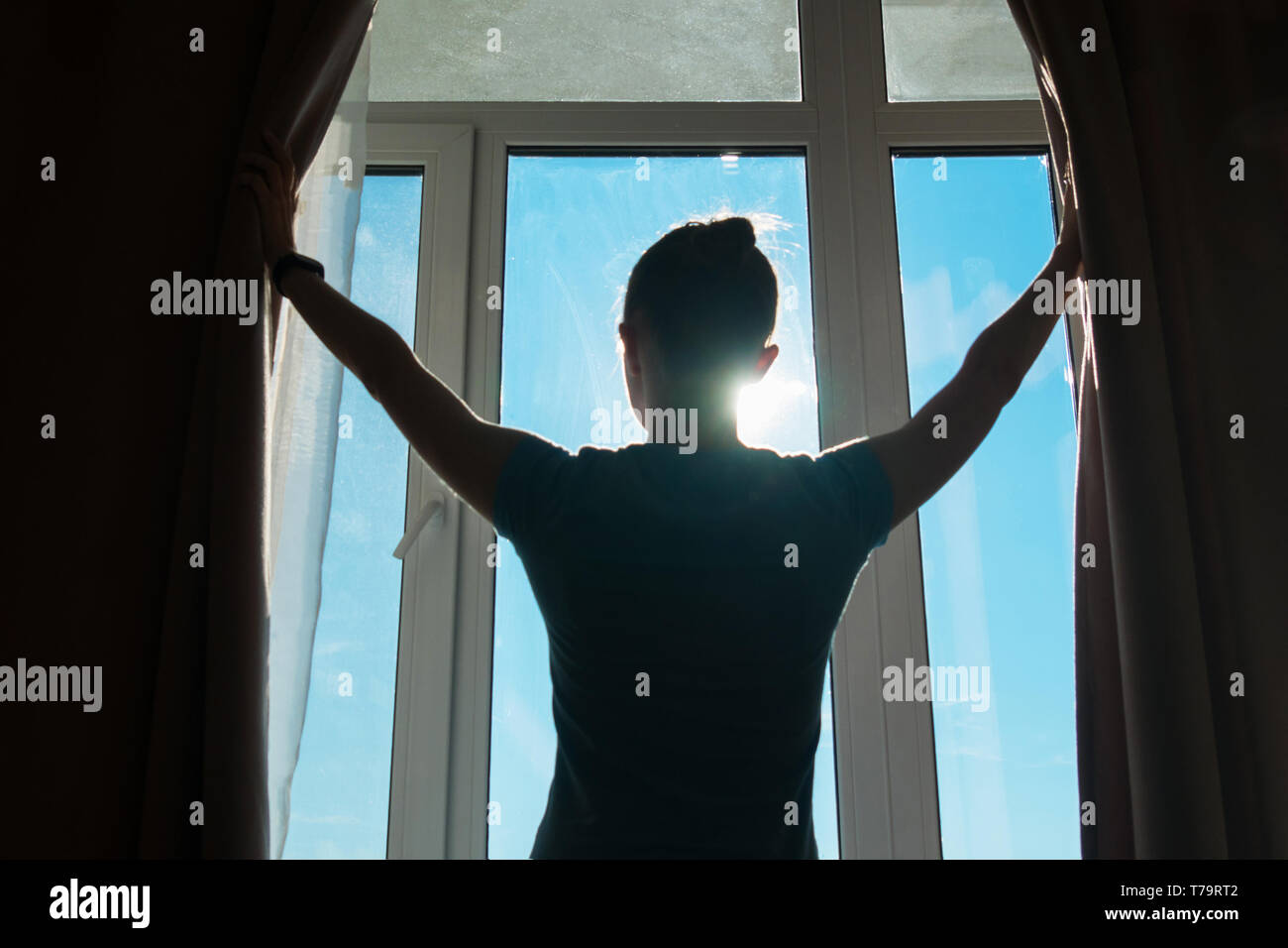 Woman opening window curtains Stock Photo - Alamy