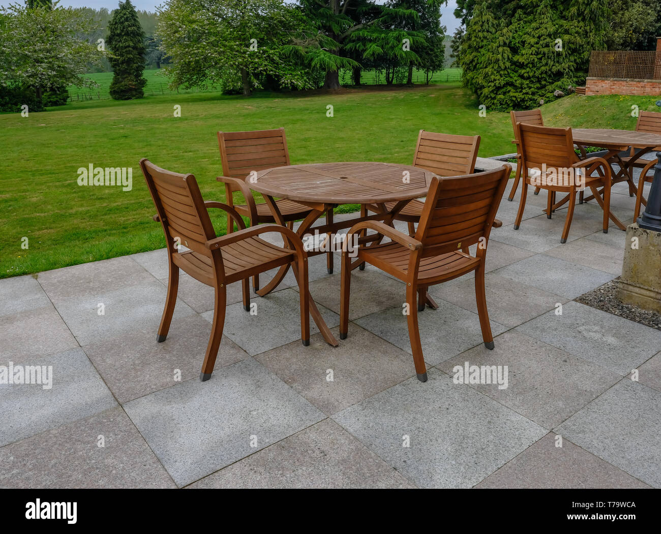 Wooden table and chairs set on a slabbed patio area with beautiful ...