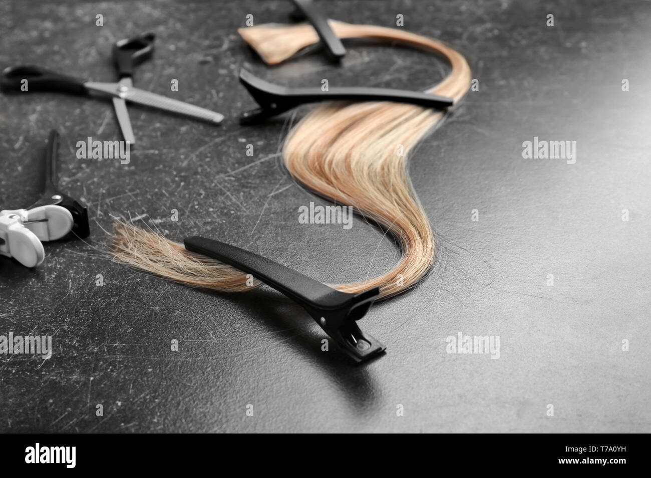 Clips with strand of blonde hair on grey background Stock Photo - Alamy
