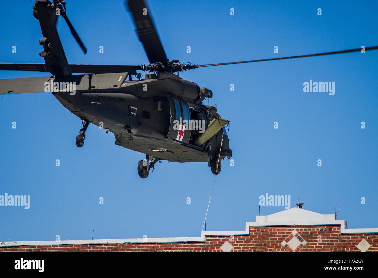 A U.S. Army UH-60 Black Hawk helicopter hoists a manikin for rooftop ...