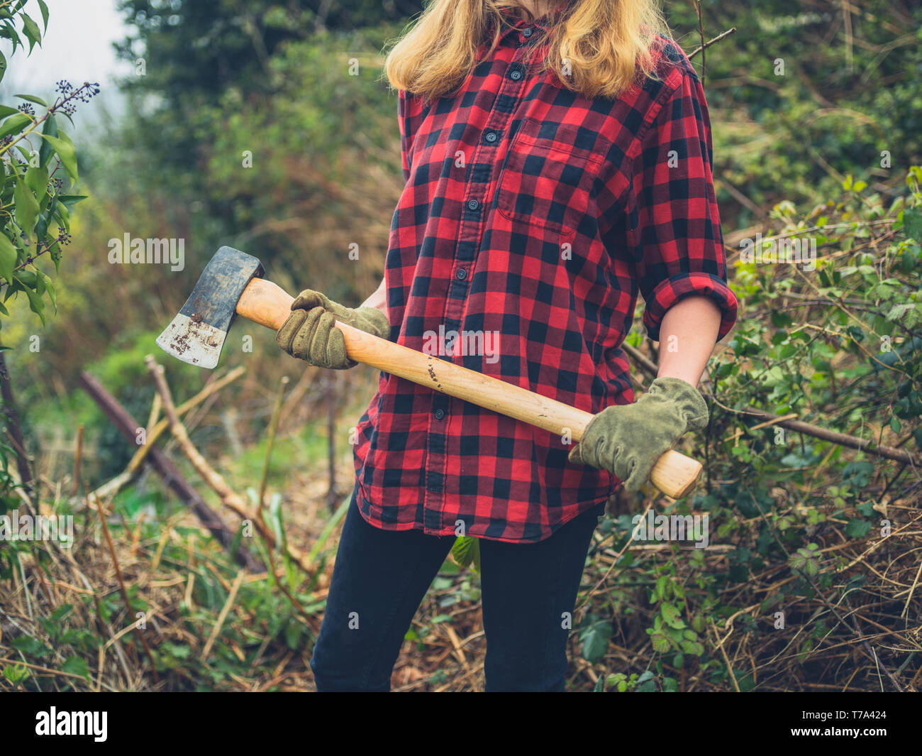 A young woman is standing in a garden holding an axe Stock Photo - Alamy