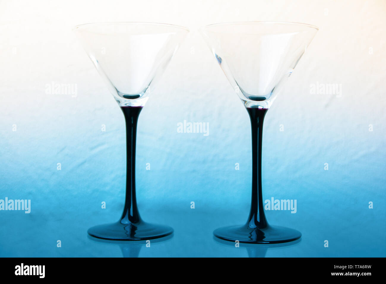 two martini glasses on black legs on a white-blue background Stock ...