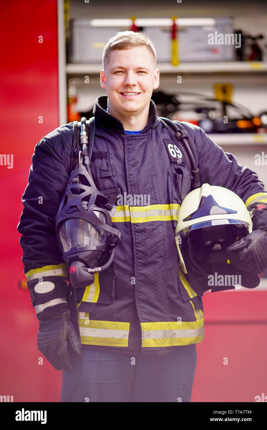 Photo of happy man firefighter with helmet in his hands against ...