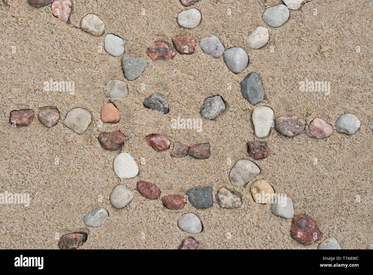 sun shape made of pebble stones on sand background texture Stock Photo ...