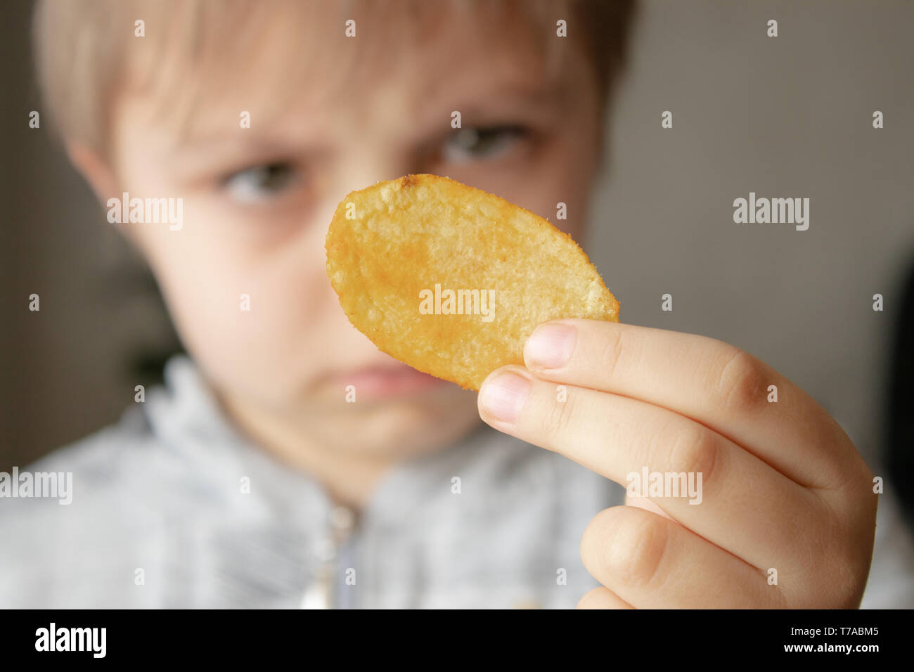 The child is holding chips. Close-up. The boy looks at the chips. Junk ...