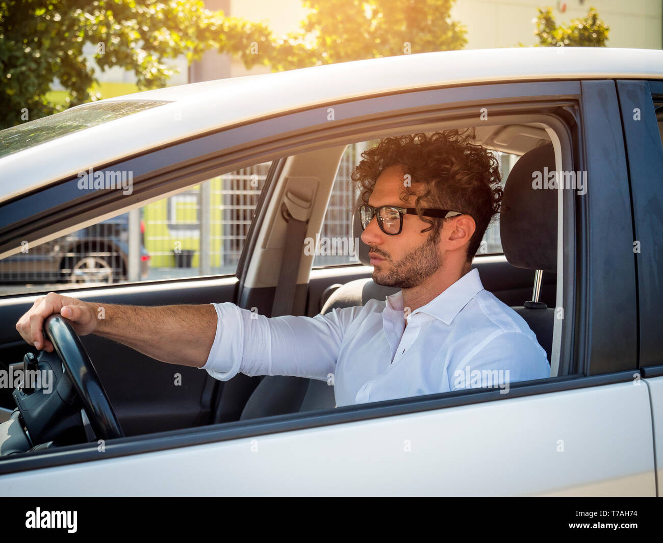 Handsome man sitting in his car, looking away Stock Photo - Alamy