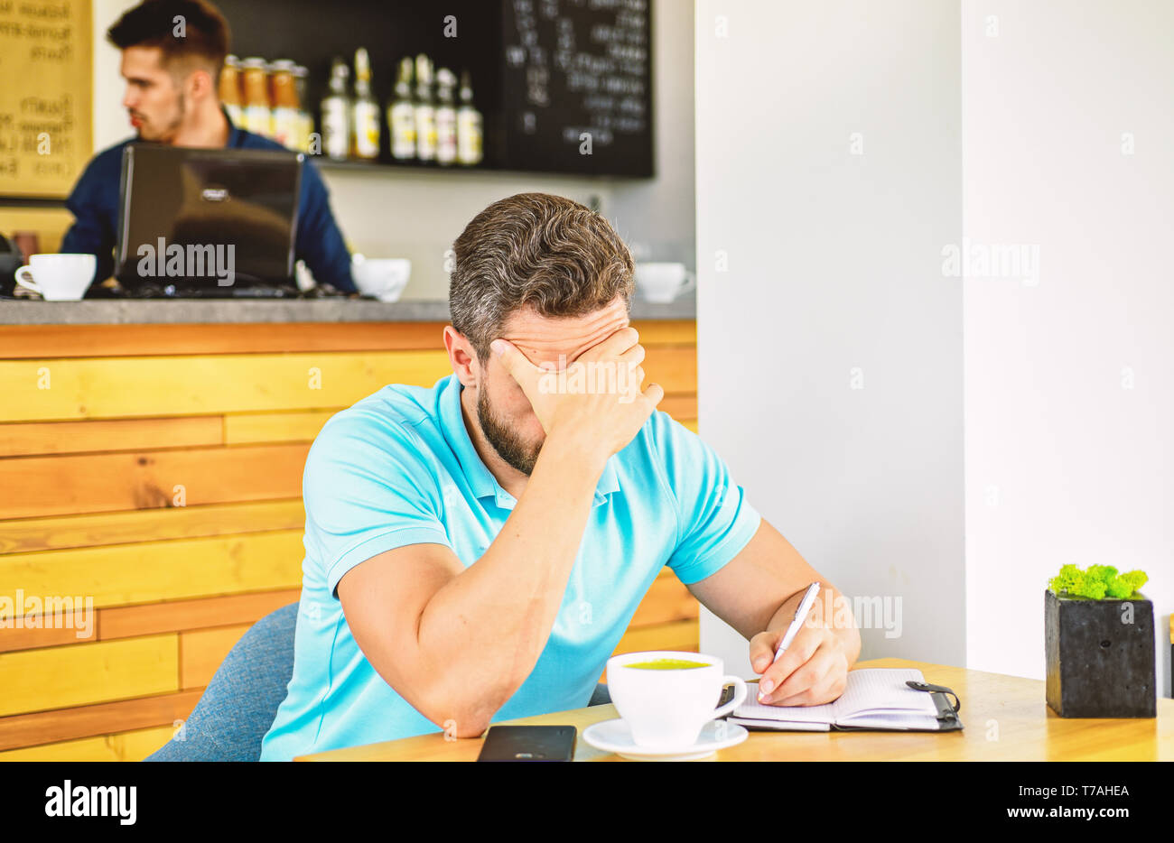 Man disappointed desperate face sit cafe with mug of coffee and notepad ...