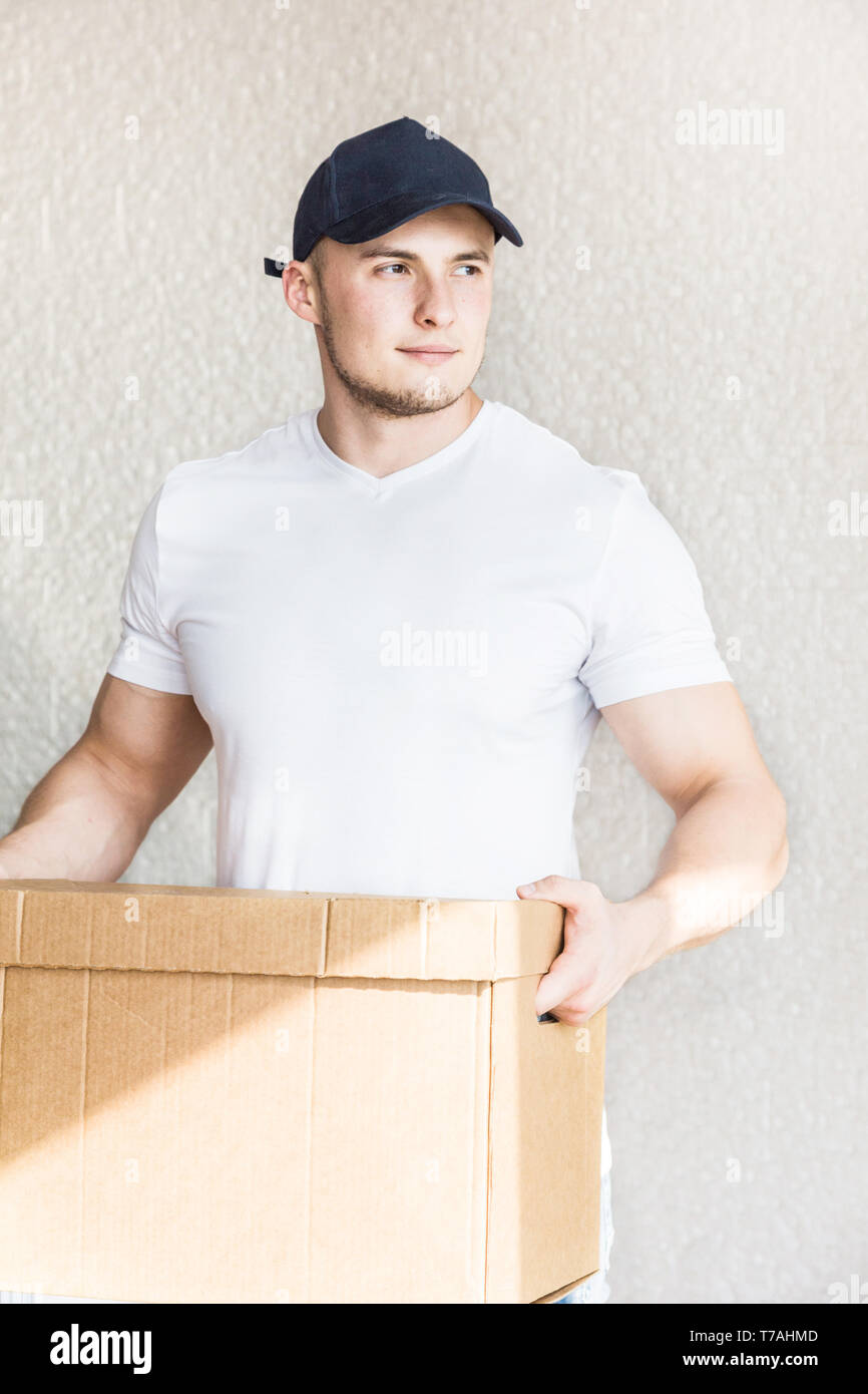 Delivery strong, muscular man loading cardboard boxes for moving to an ...