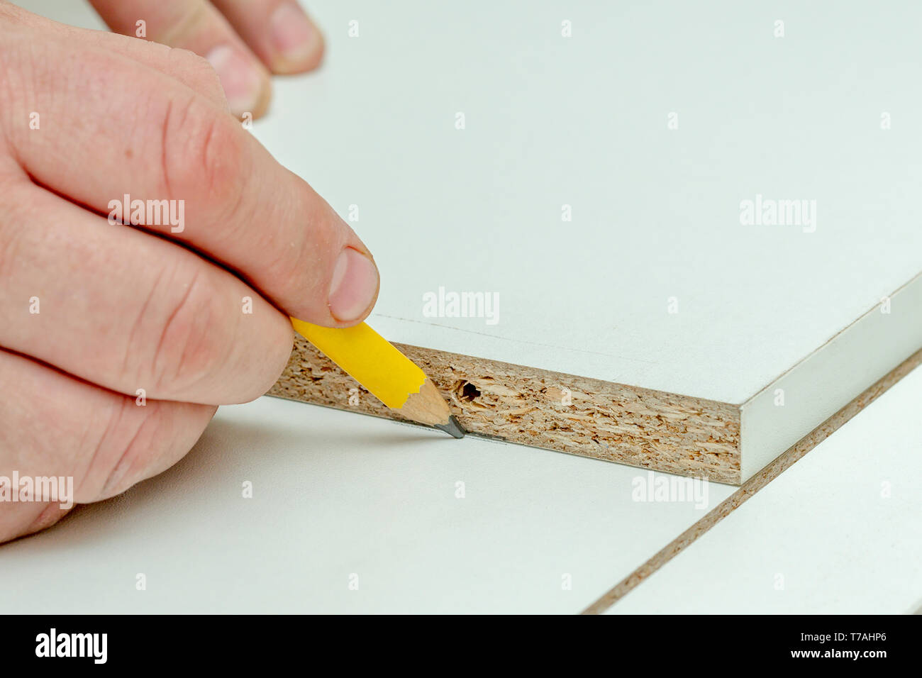 A person marks a wooden board with a pencil and ruler Stock Photo - Alamy