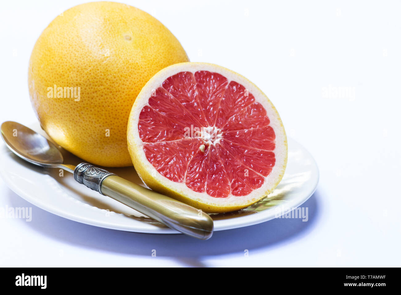 Whole and half grapefruit in a plate on white background Stock Photo ...