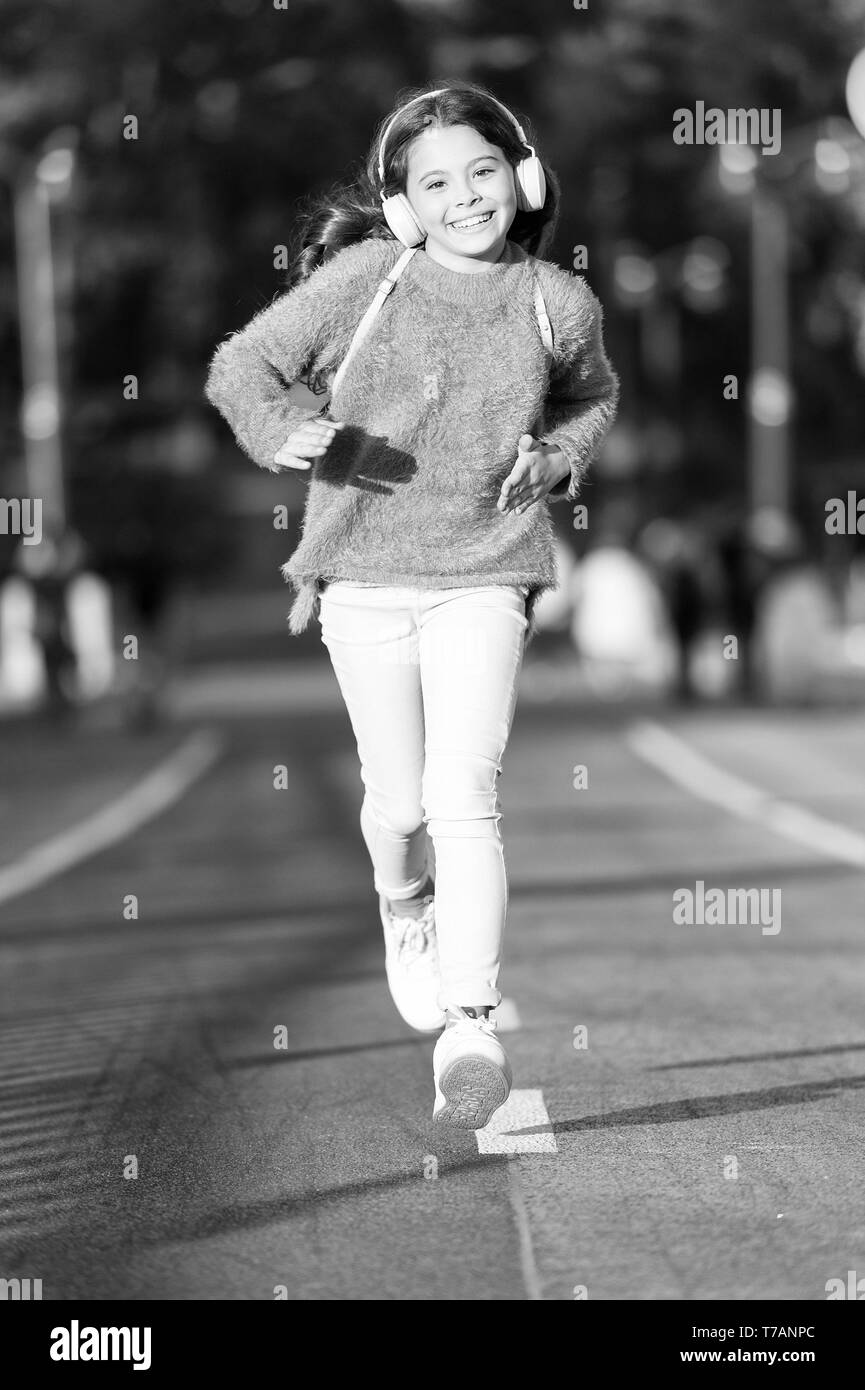 Keep moving. Girl child on running track. Little child enjoy sport ...