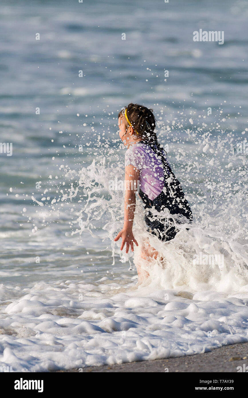 A young girl enjoying playing in the sea at Fistral Beach in Newquay in ...