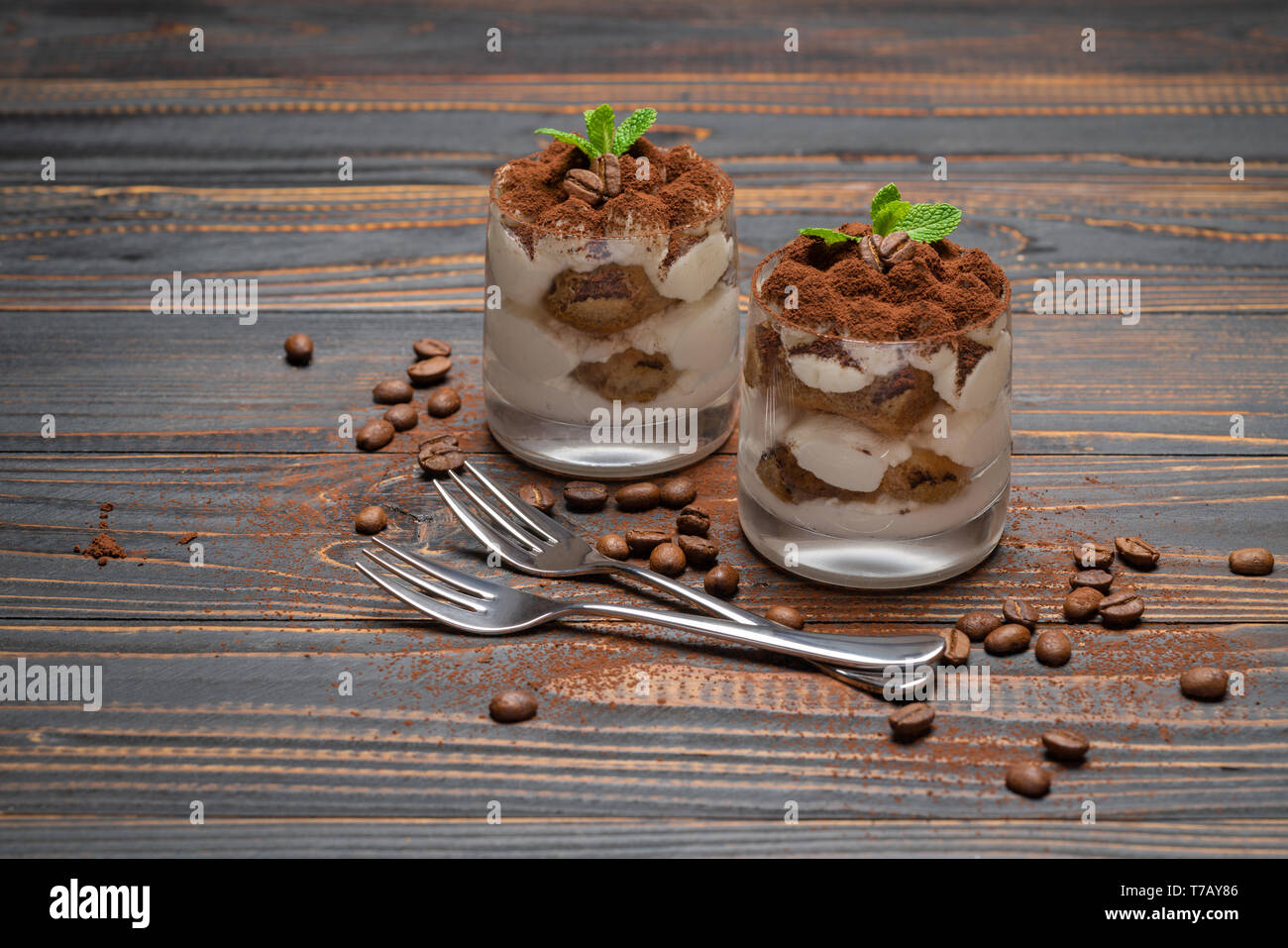 two portions Classic tiramisu dessert in a glass on wooden background ...
