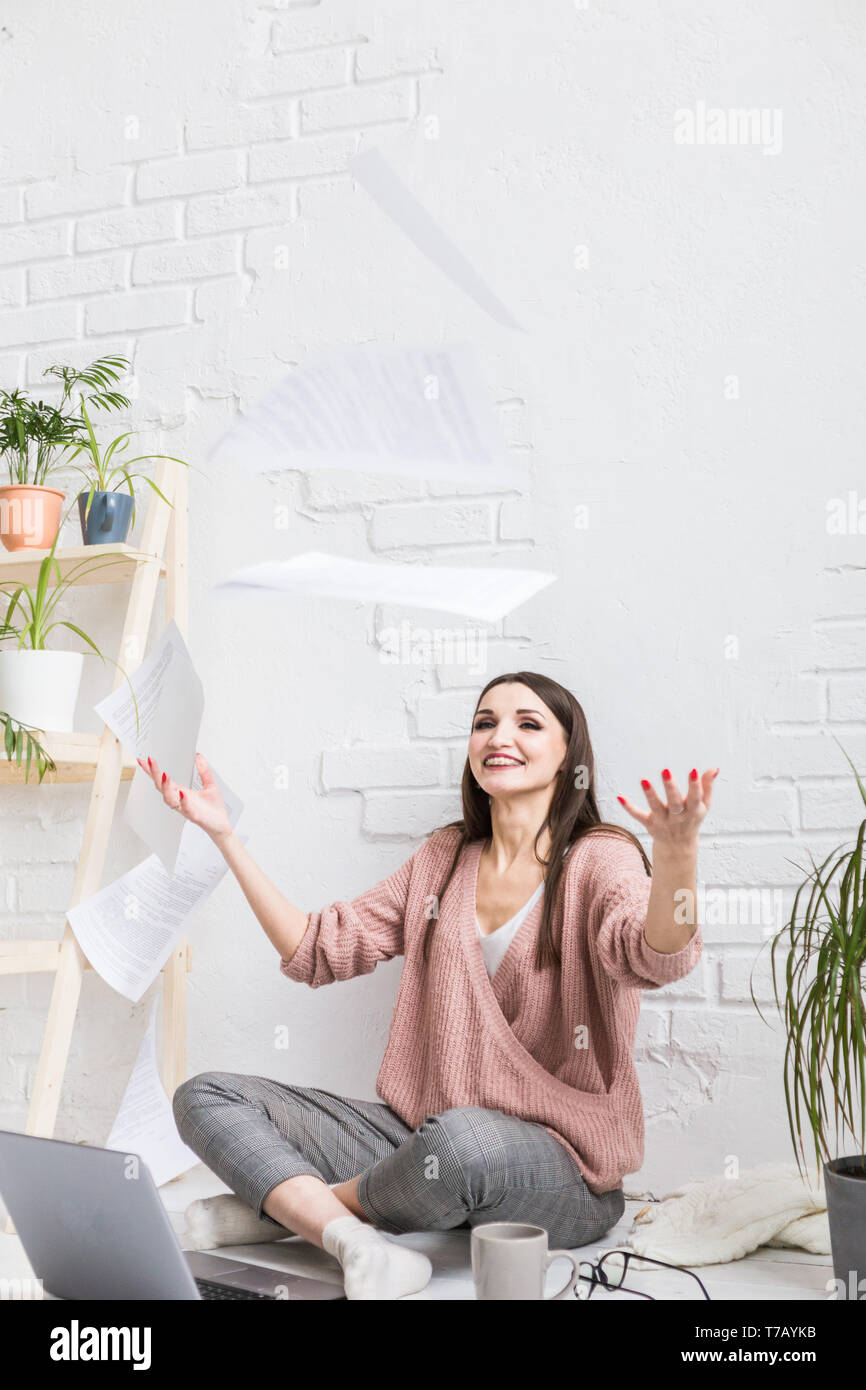 A young happy woman throws up a bunch of pieces of paper and documents ...