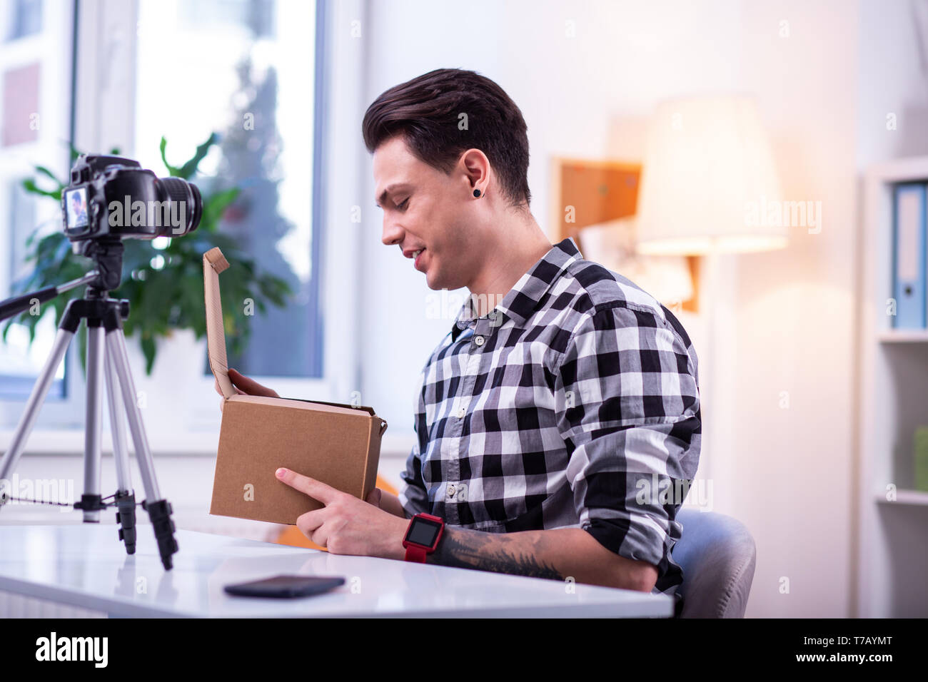 Curious short-haired stylish guy opening box with new product Stock ...