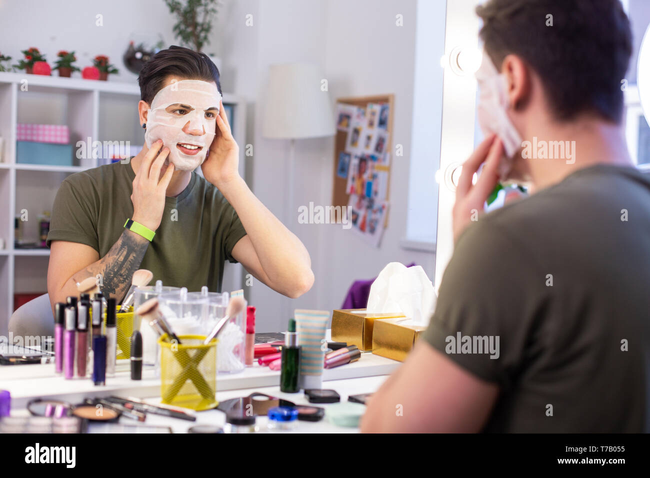 Satisfied short-haired vlogger touching his face mask Stock Photo - Alamy