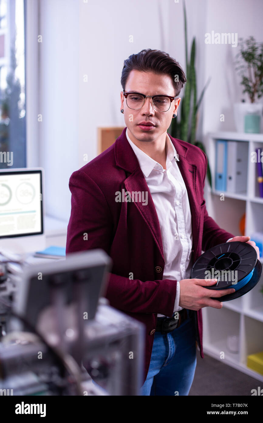 Interested good-looking young man working with complicated technique ...