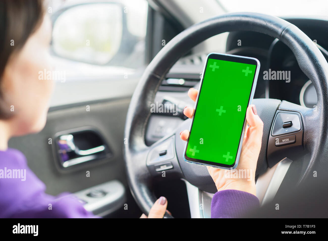 Young female driver using touch screen smartphone in a car. green ...