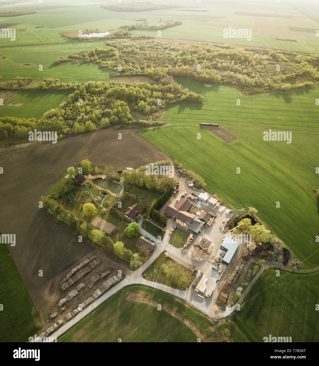 Aerial view of farmstead and sawmill surrounded by green fields ...
