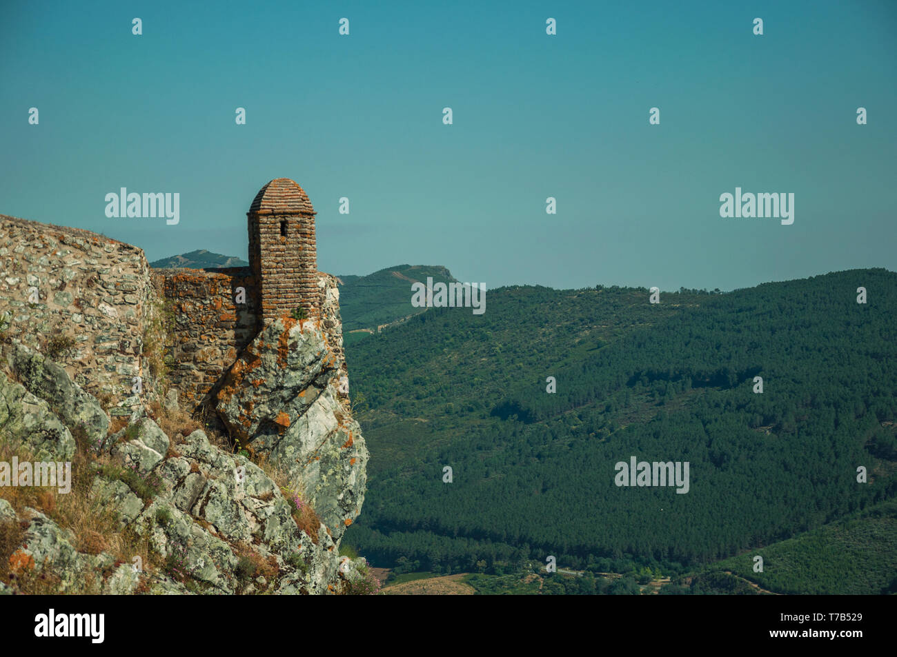 Small watchtower and stone wall over rocky cliff with hilly landscape ...