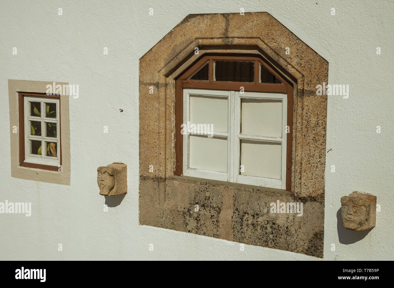 Glazed window with decorative stone frame in an old house facade with ...
