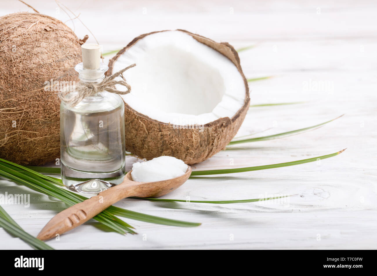 Coconut shell pieces and palm leaves on white wooden table Stock Photo ...