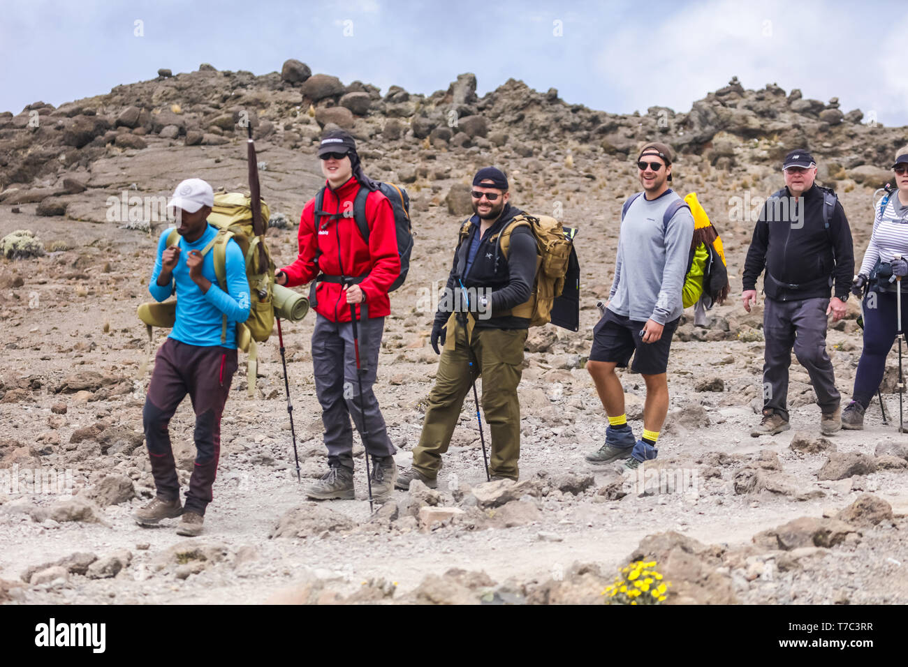 Happy tourists standing near the hill with mountain equipment, wearing ...