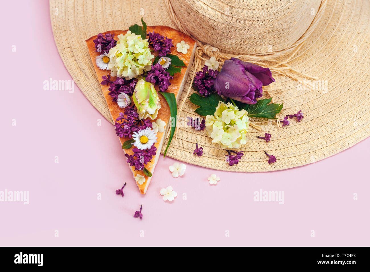 Slice of pizza on a pink background with straw hat and spring flowers ...