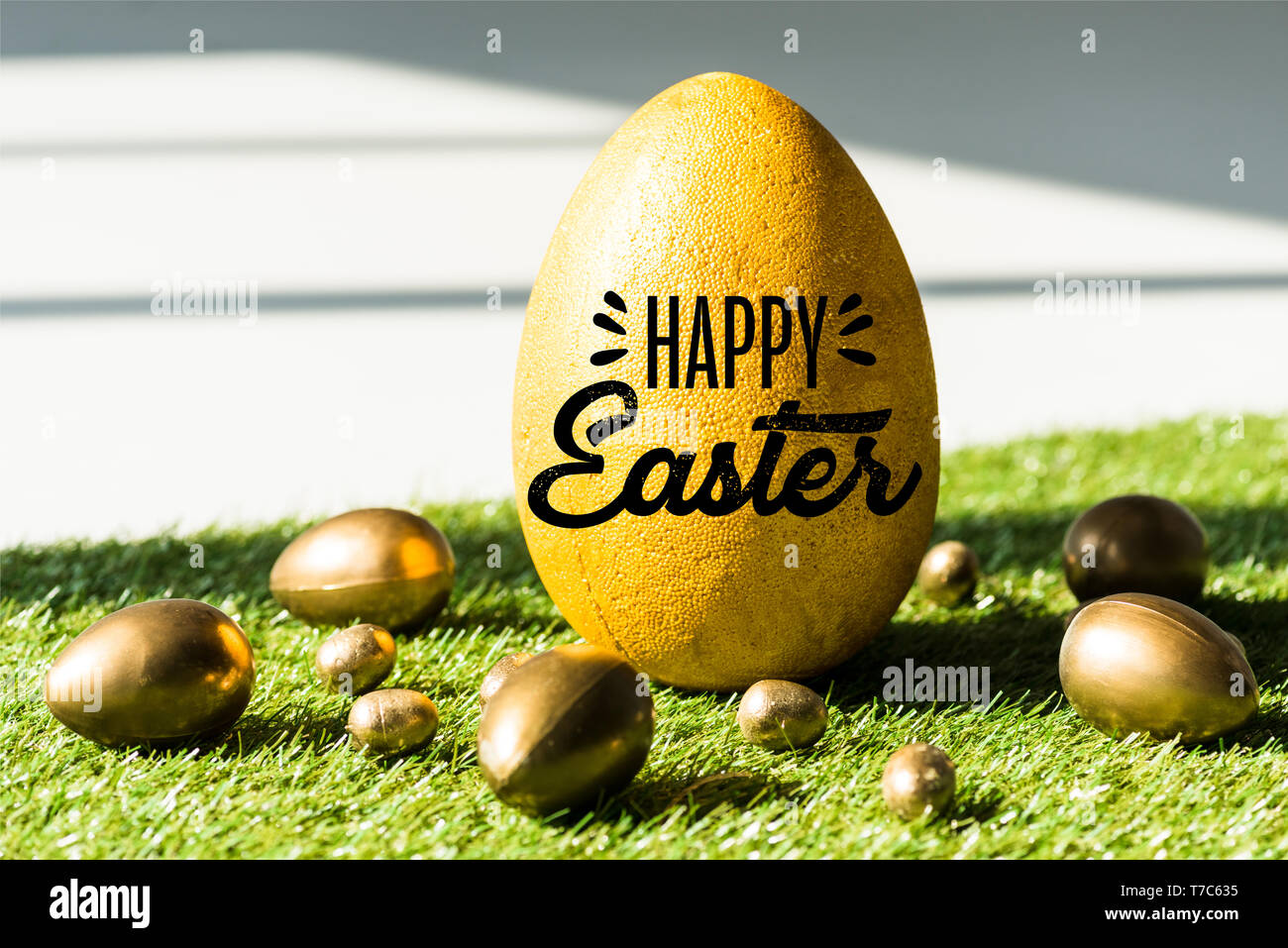 big ostrich egg with happy Easter lettering near golden chicken and ...