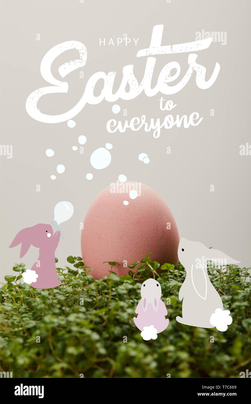 pink painted chicken egg on green grass with happy Easter to everyone ...