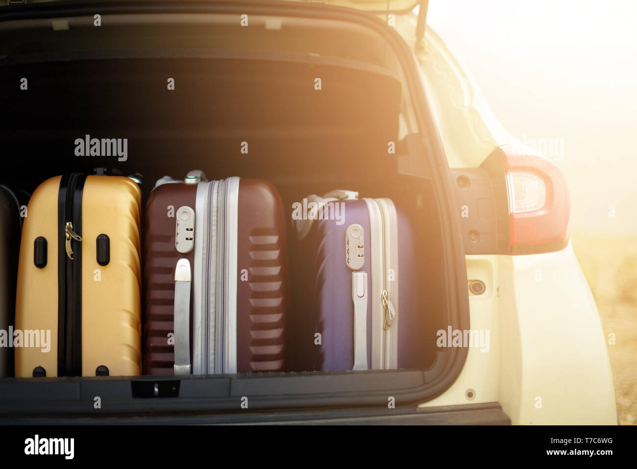 Opened car trunk full of suitcases in sunlight effect. Travel ...
