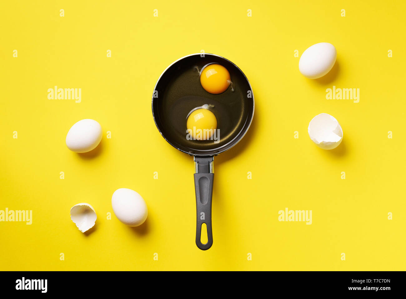 Food concept with two eggs, shells, pan on yellow background. Top view ...