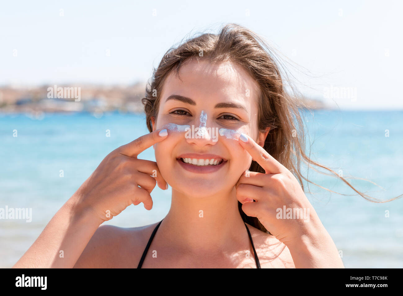 Tanned Woman Protects Her Face With Sun Cream From Sunburn At The Beach