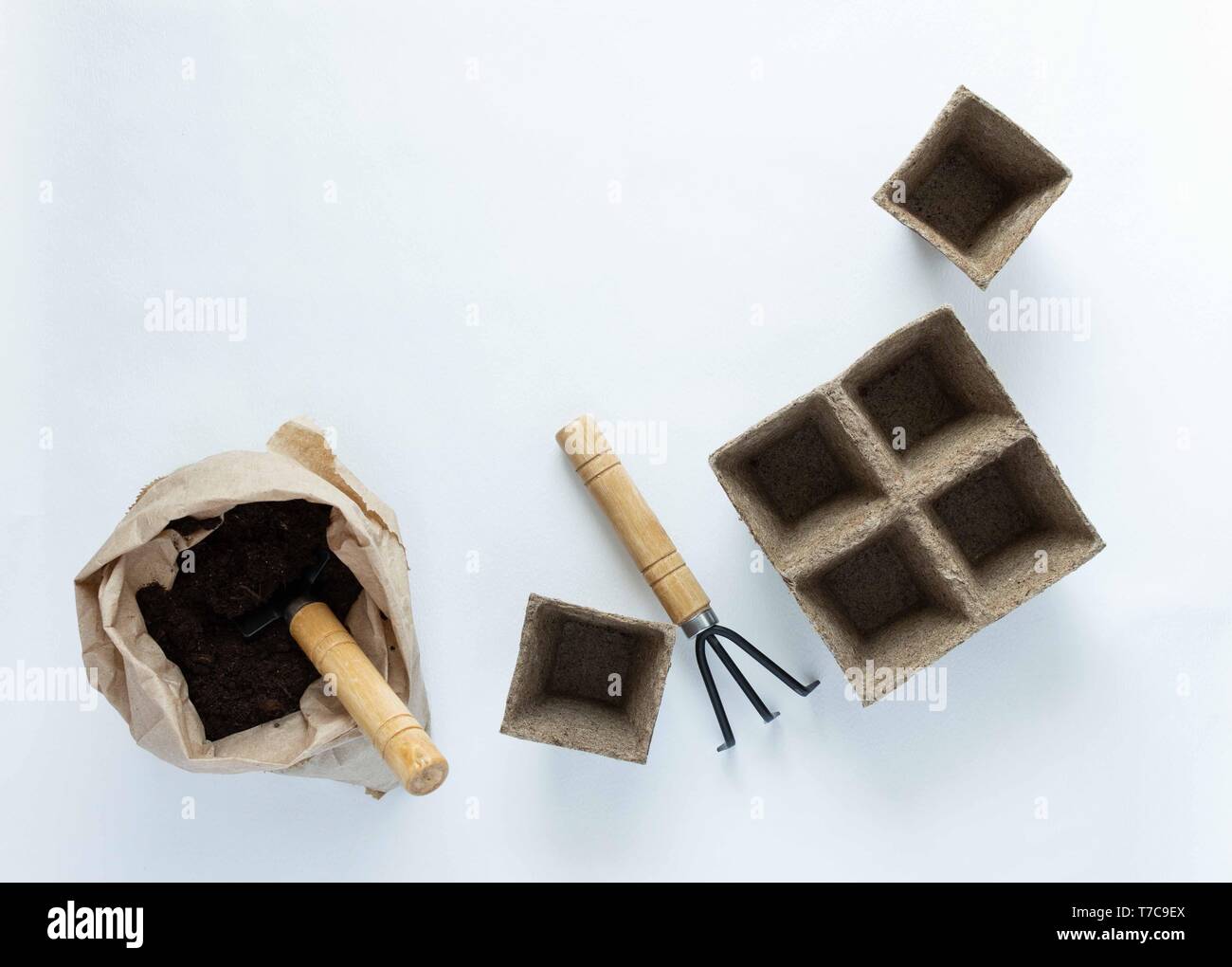 Eco friendly empty pots for seedlings and rakes on white background ...