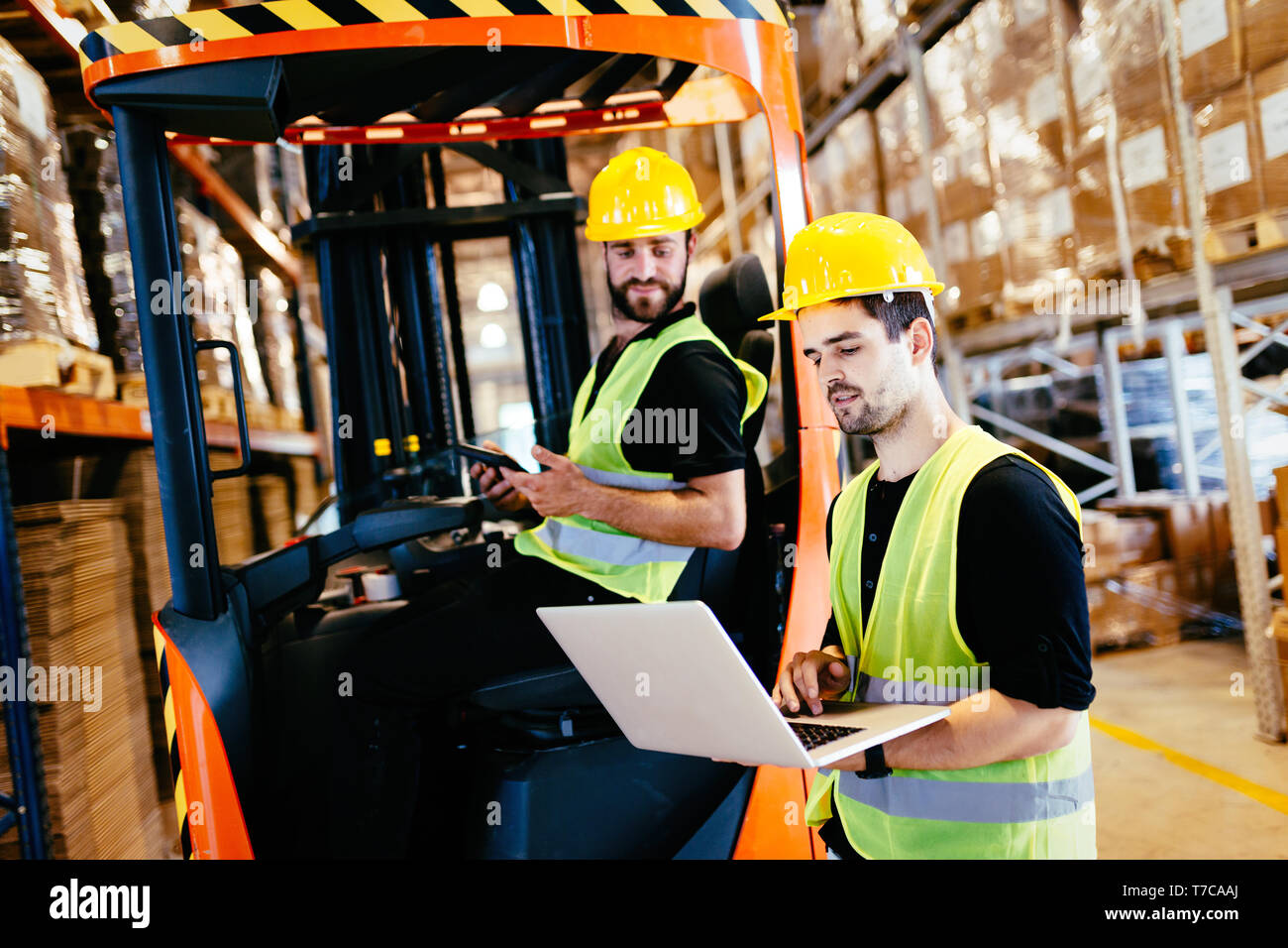 Warehouse workers working together with forklift loader Stock Photo - Alamy