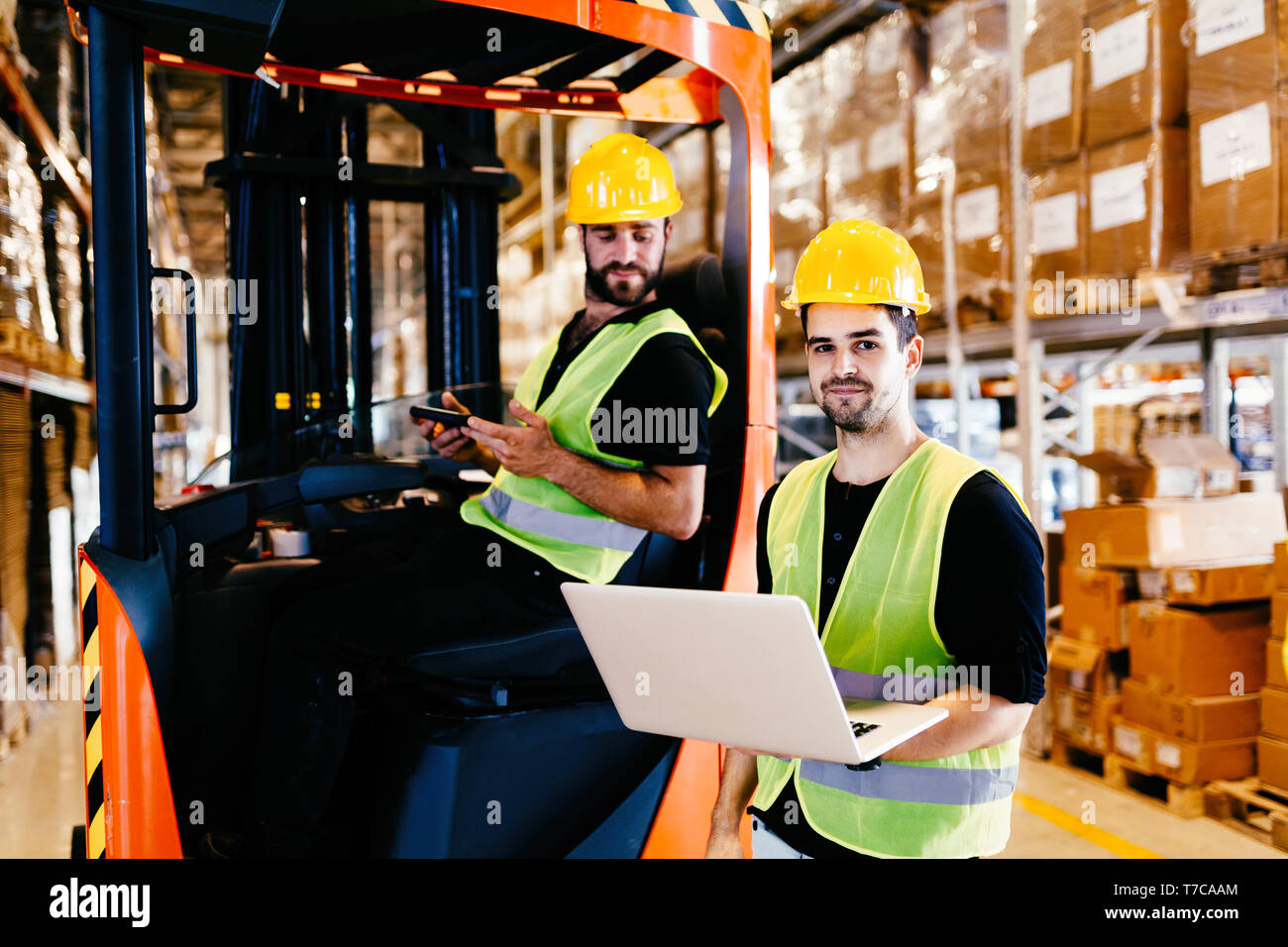 Warehouse workers working together with forklift loader Stock Photo - Alamy