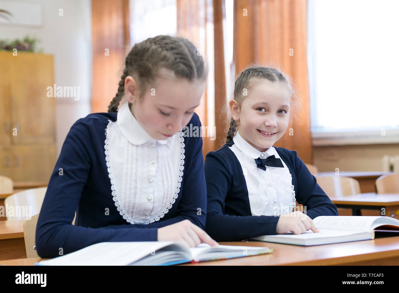 Hair braided in braids. Schoolgirl girls write in a notebook while ...