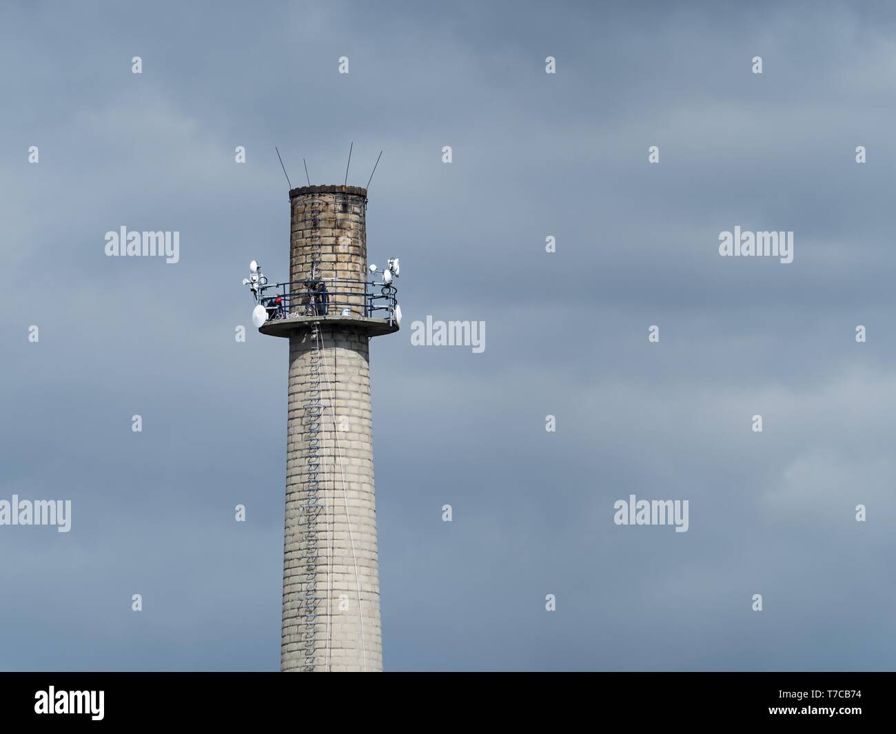 Tall factory chimney made of white bricks. Iron degrees lead to the top ...