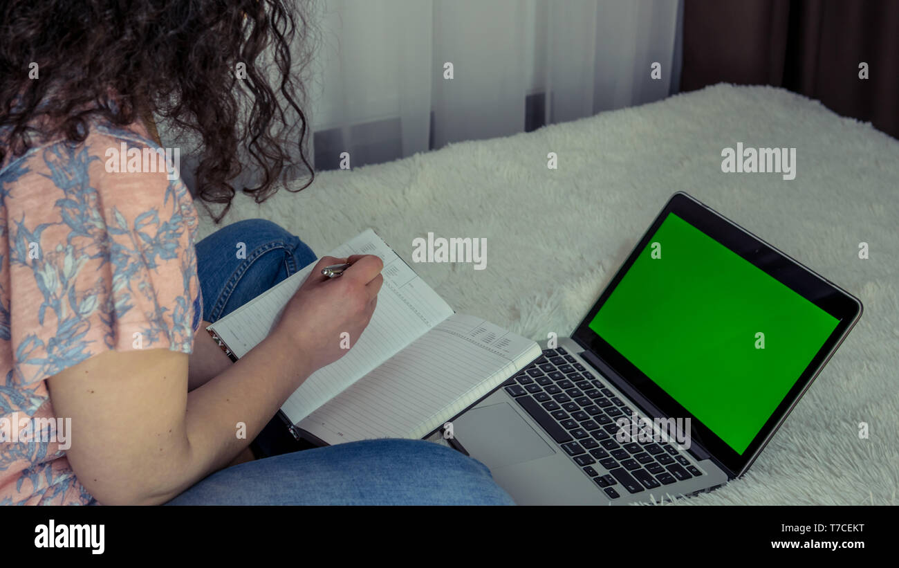 The young woman uses a laptop at home and a cup of tea in the hand. The ...