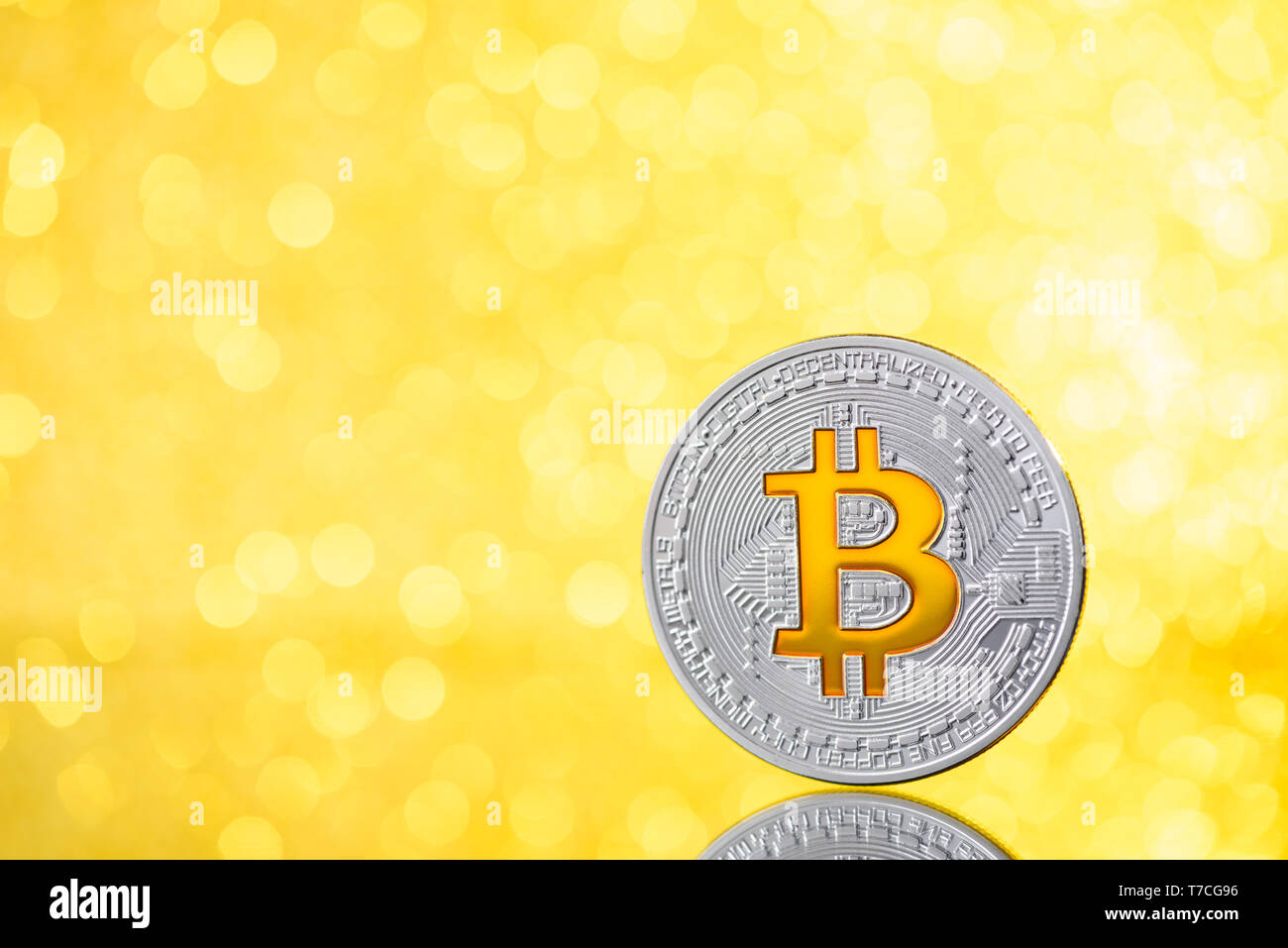 Silver bitcoin coin with golden bitcoin symbol on golden shiny glitter ...