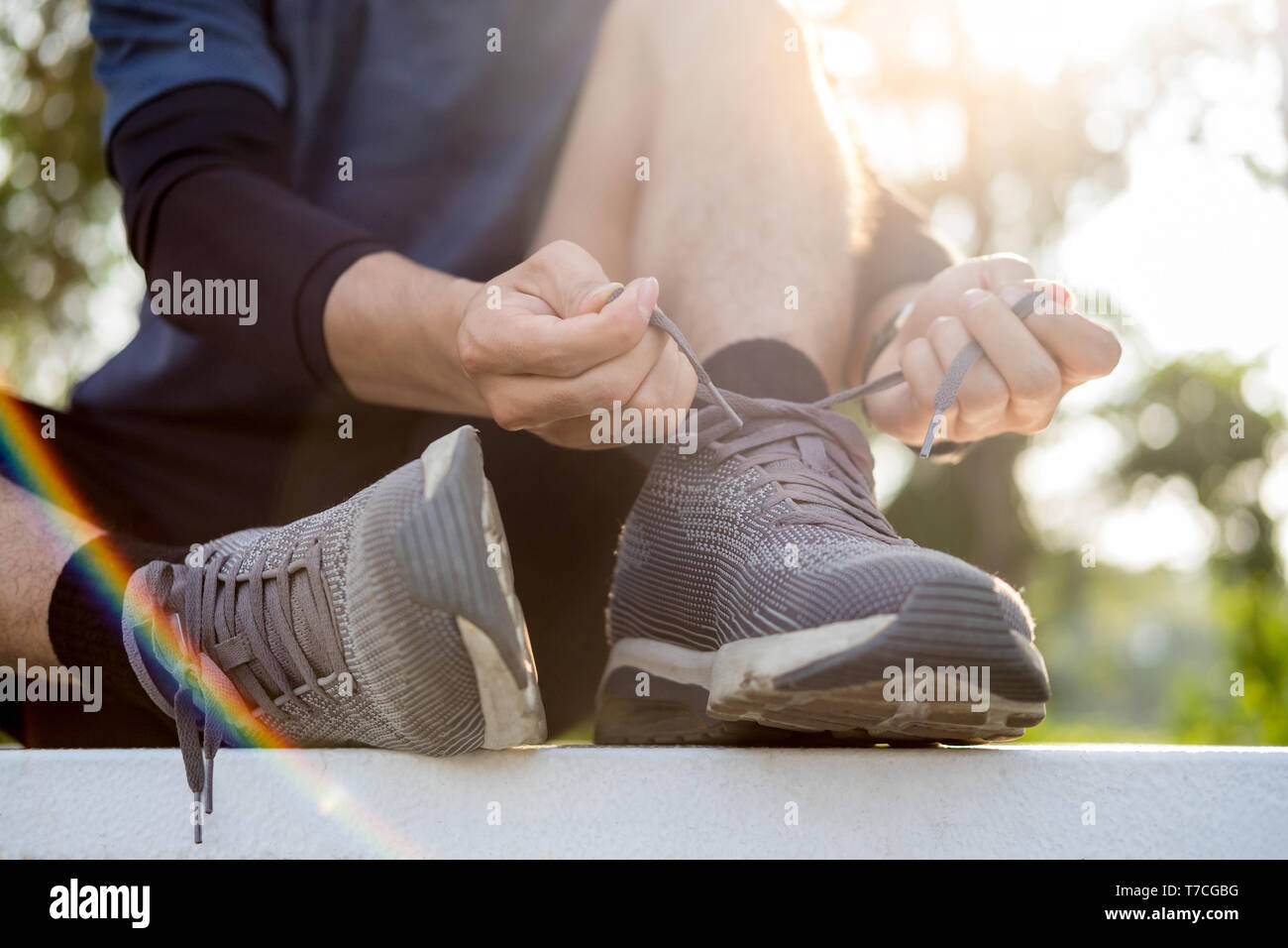 Male athlete tying shoe laces in minimalistic barefoot sneakers getting ...