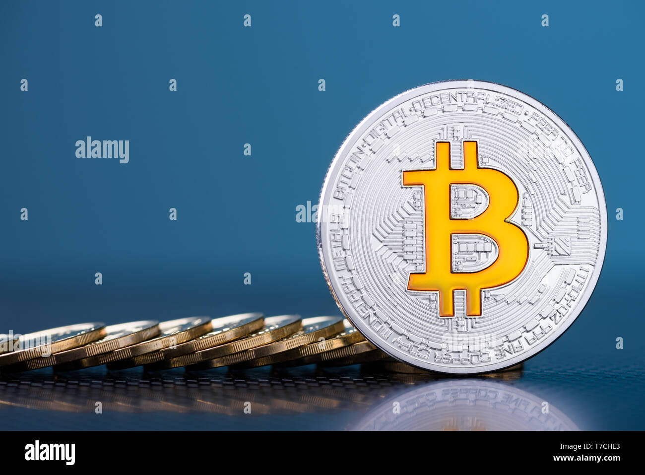 Shiny silver bitcoin with bit logo symbol and coins on dark blue ...