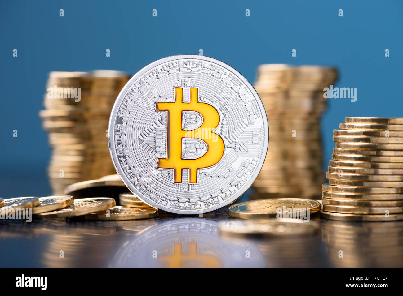 Shiny silver bitcoin with bit logo symbol and coins stacks on dark blue ...
