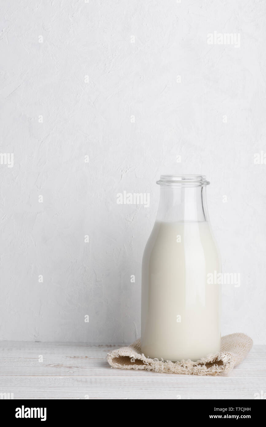 Bottle of milk on a sack cloth on white wooden table background ...