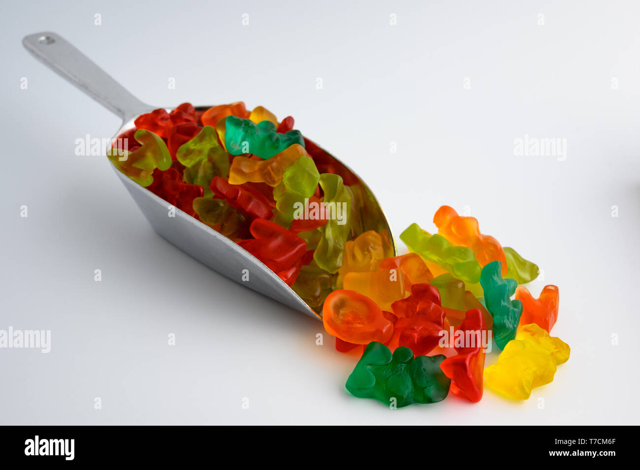 Metal scoop full of colorful gummy candies on white background Stock ...