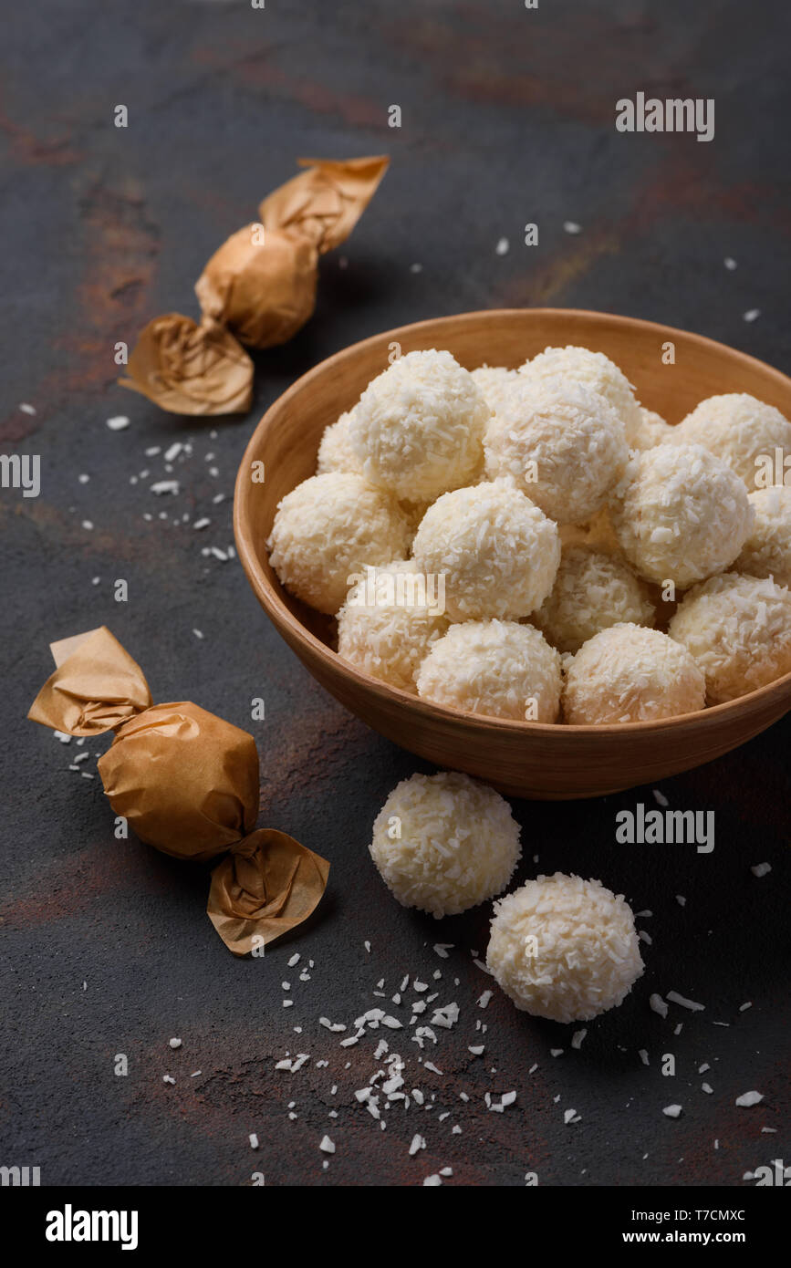 Coconut candies in bowl and wrapped on dark table background Stock ...